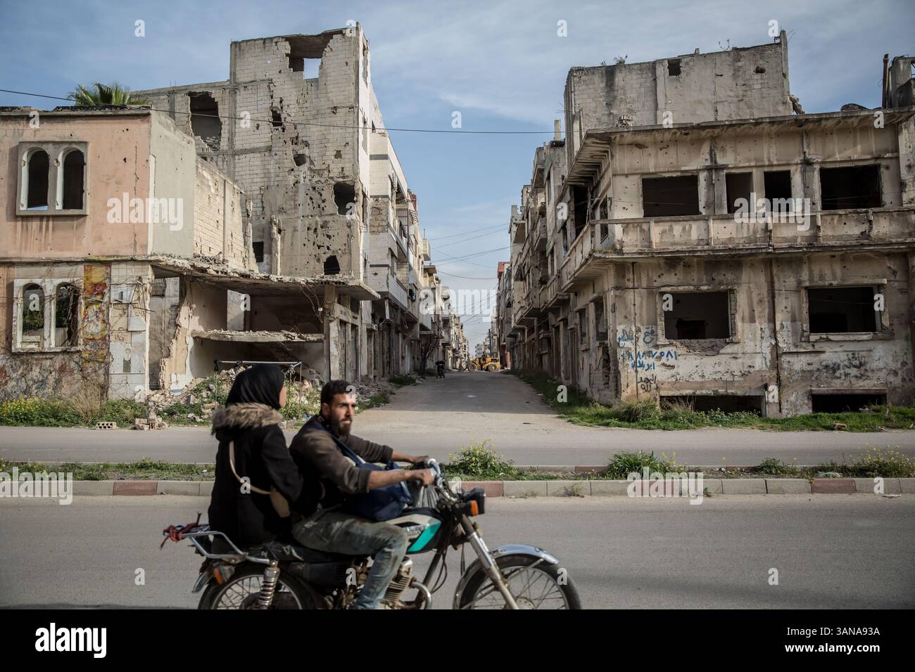 A man and woman ride through a damaged neighbourhood in Homs. Homs ...