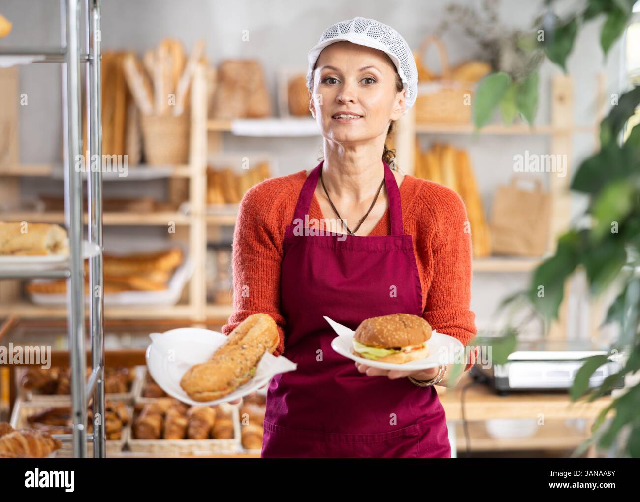 Positive woman baker holding plates with pastry Stock Photo - Alamy