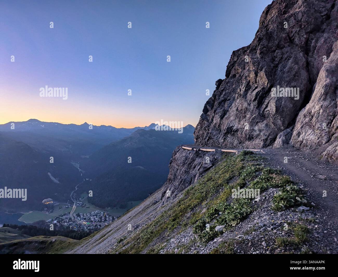A winding dirt road that ascends the steep side of a mountain, leading ...