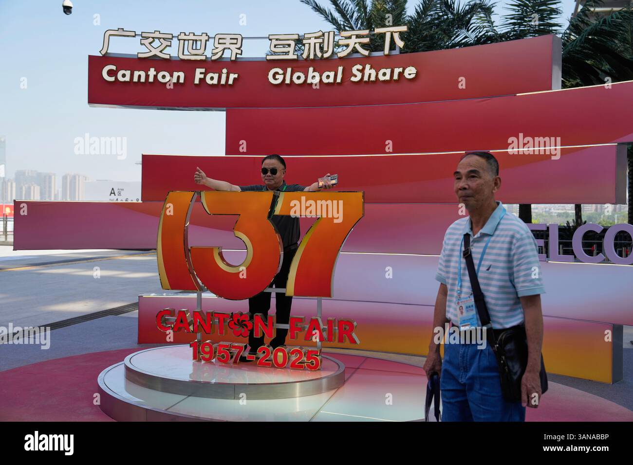 A visitor poses for photos near the sign for the 137th Canton Fair in ...