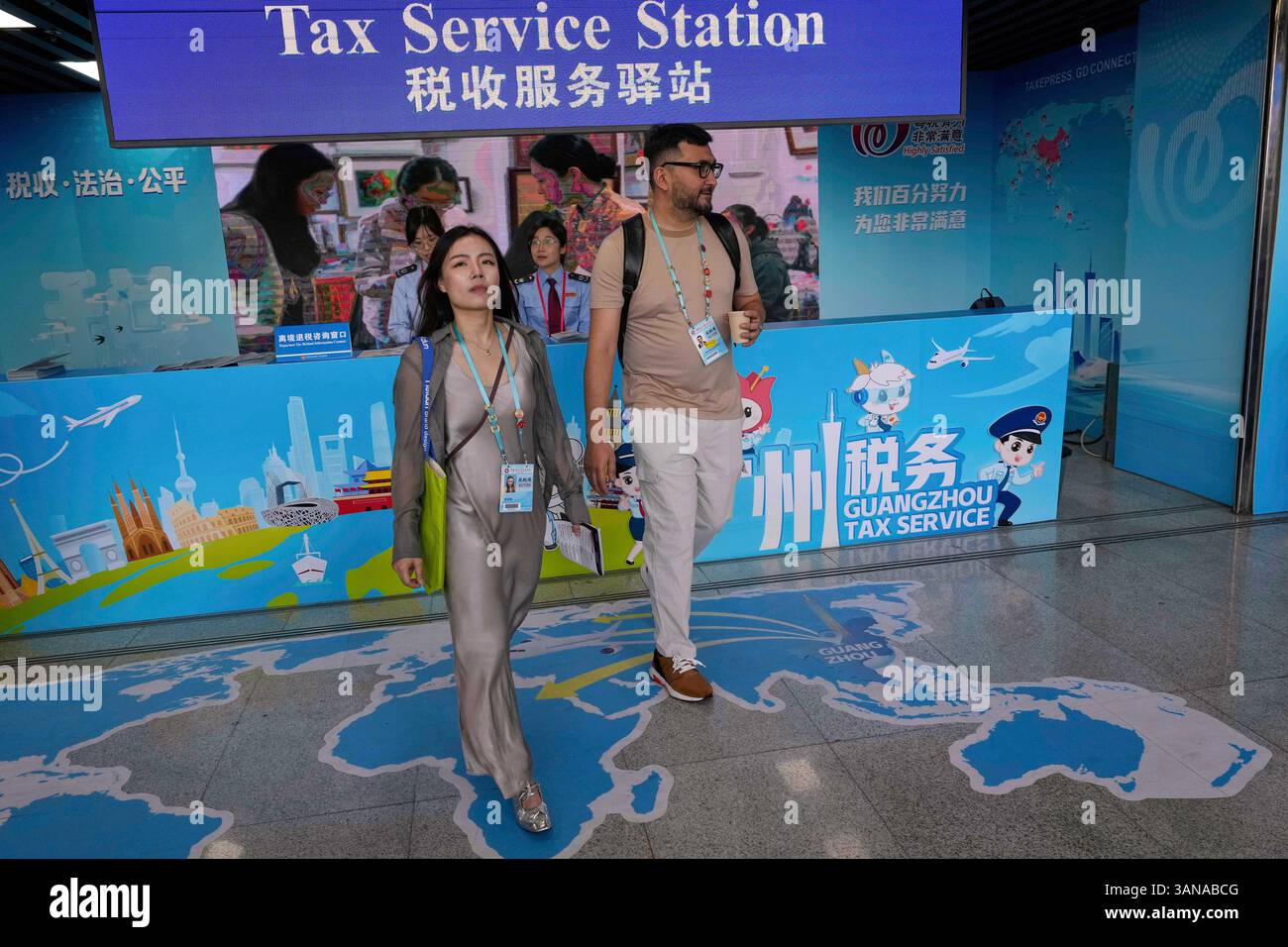 Visitors walk by the Guangzhou Tax Service booth at the 137th Canton ...