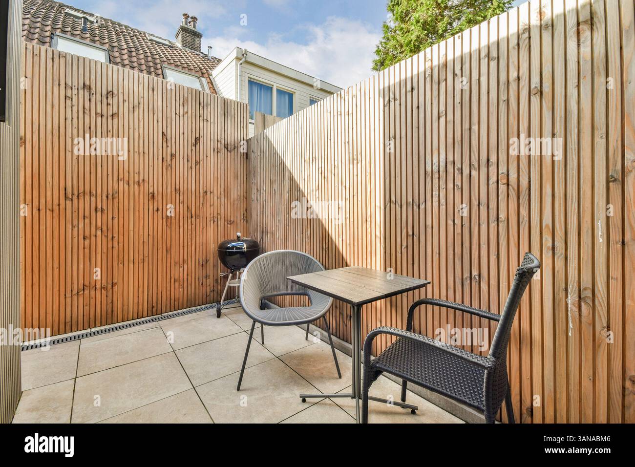 A serene outdoor patio features wooden fencing, a small table with ...