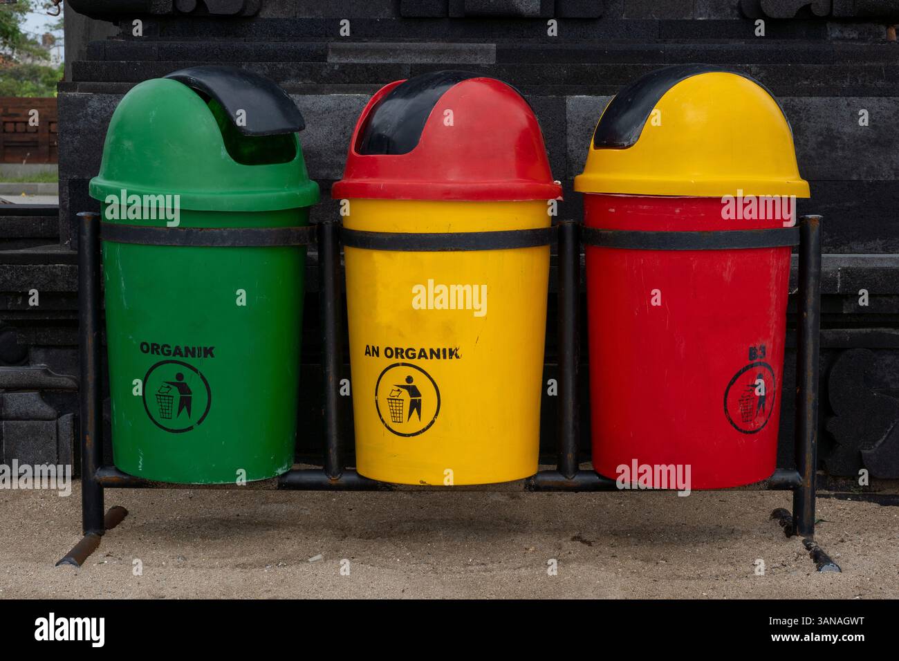 Three trash cans are lined up in a row, each with a different color ...