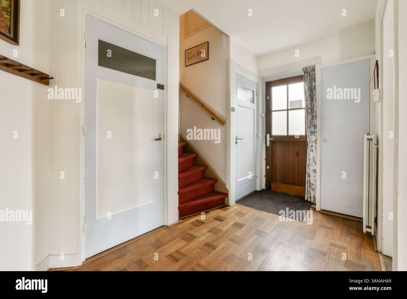 A well-lit interior hallway featuring a staircase, classic doors, and ...