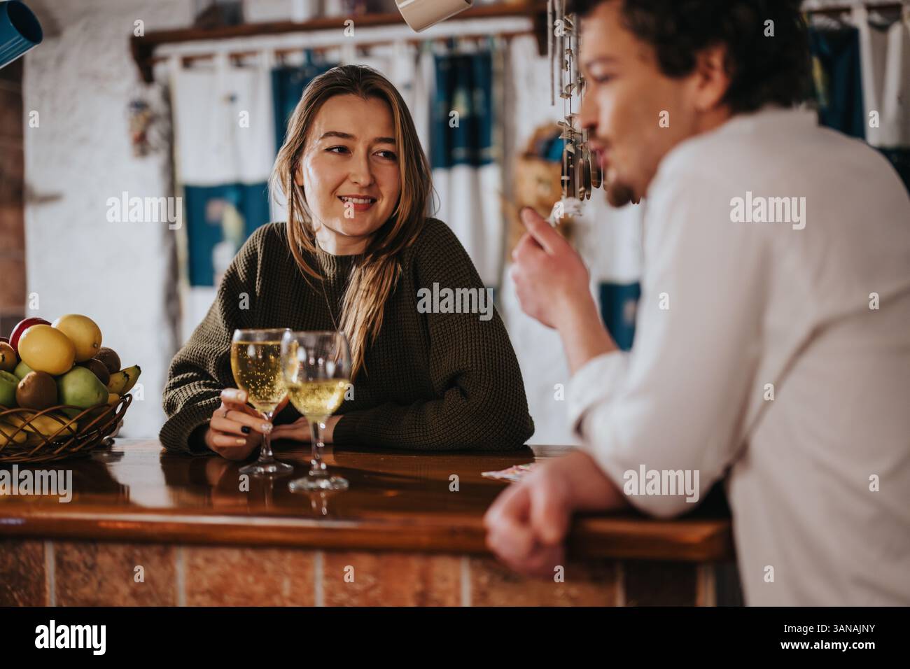 Two friends sharing drinks and conversation at a cozy kitchen bar Stock ...