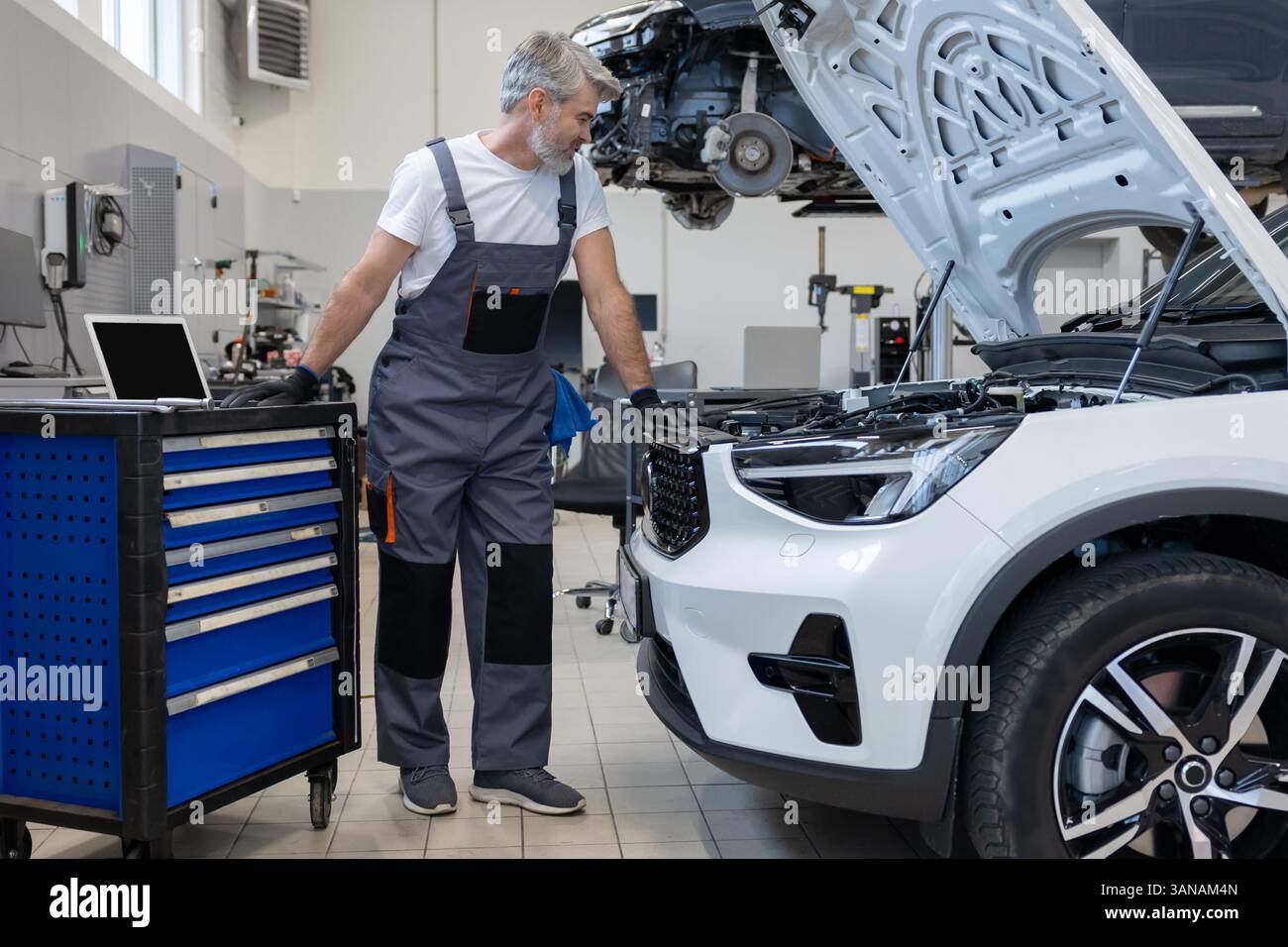 Automotive technician in uniform using laptop for diagnostic check on ...