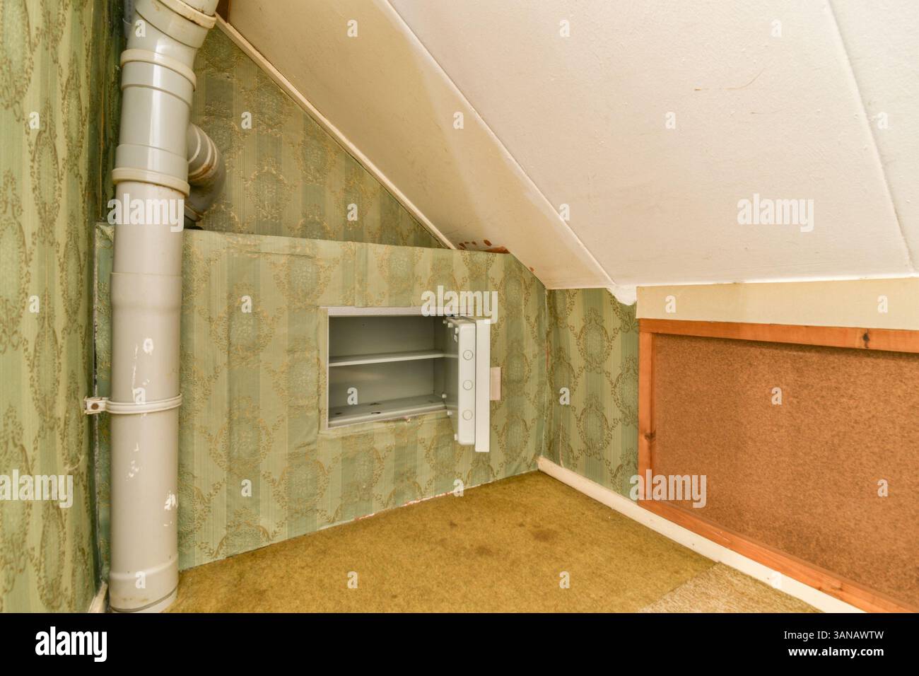 A view of an attic featuring vintage wallpaper, a wall-safe, and ...