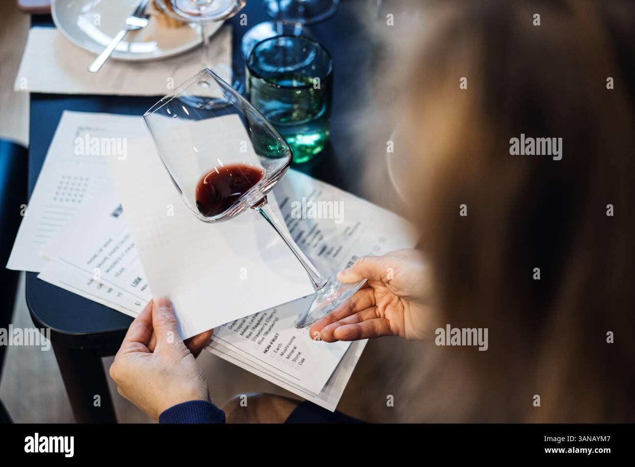 Glass of red wine tilted above printed tasting notes on a restaurant ...