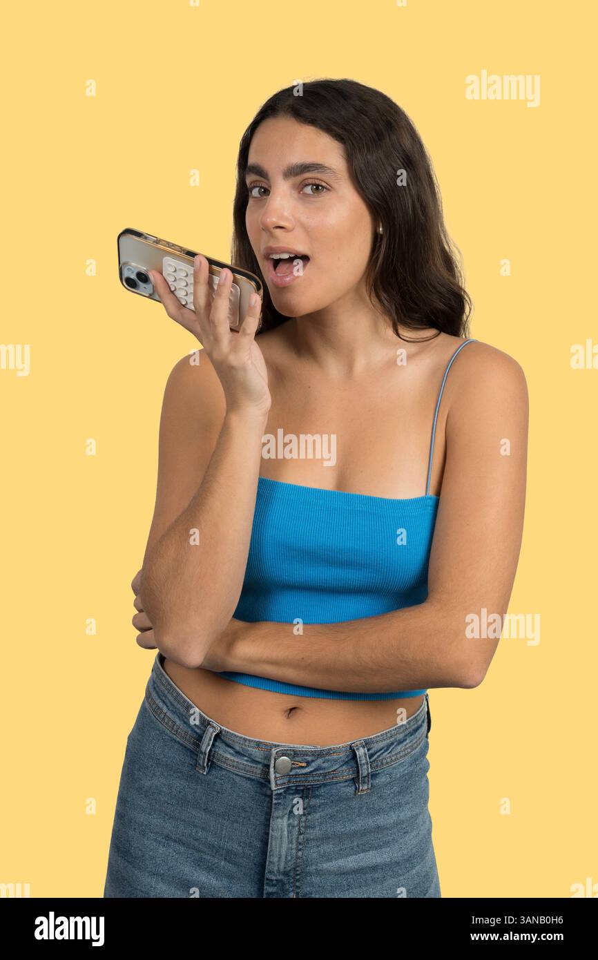 Young woman recording voice message on smartphone with pop socket grip ...