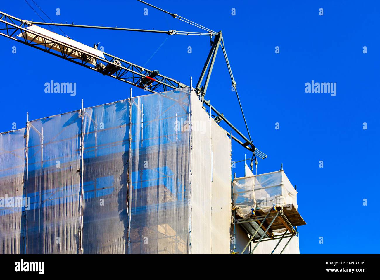 Tall building under construction is wrapped in white scaffolding and ...