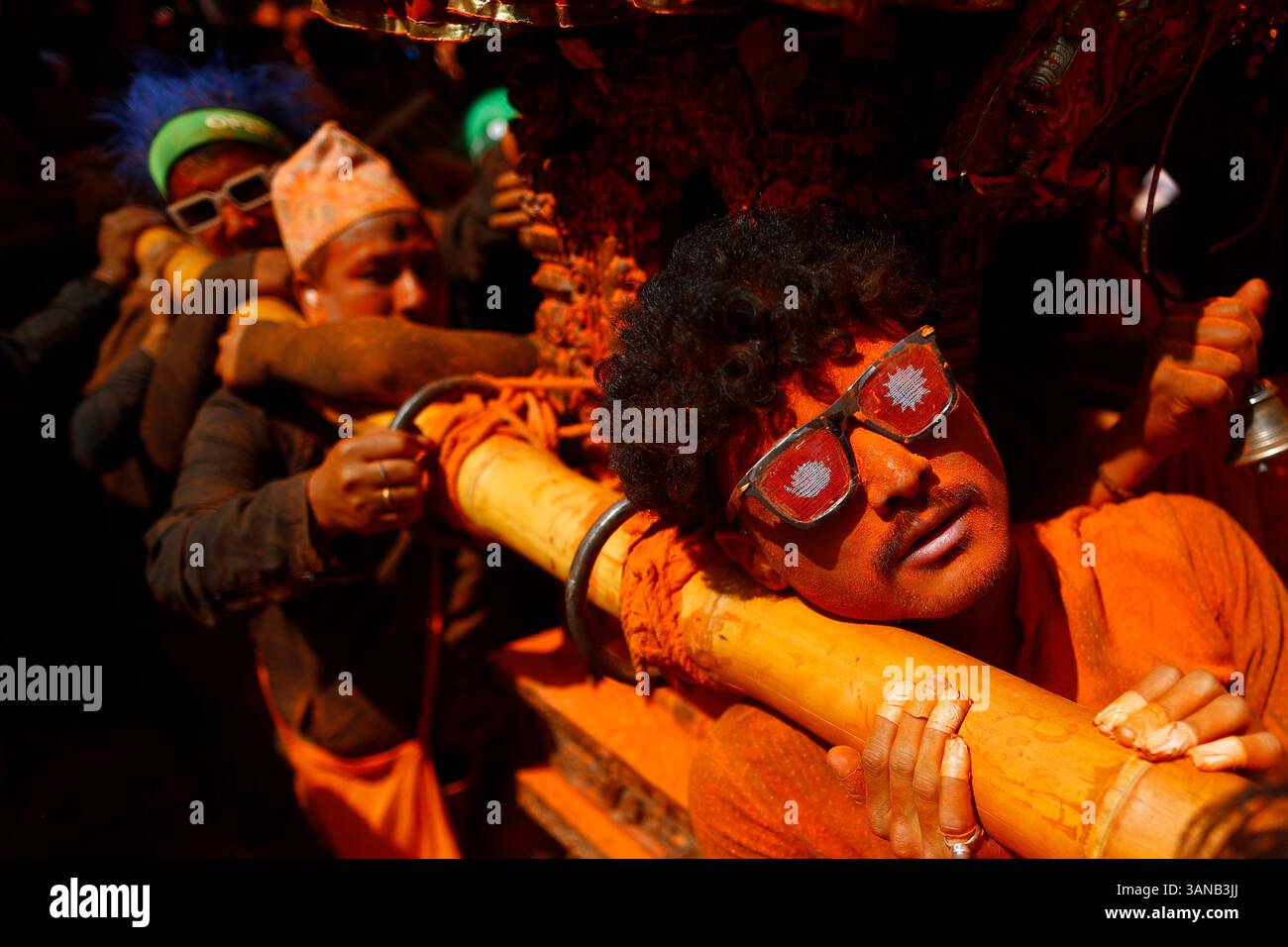 A Nepalese reveler wearing glasses of the Nepali flag carries a chariot ...