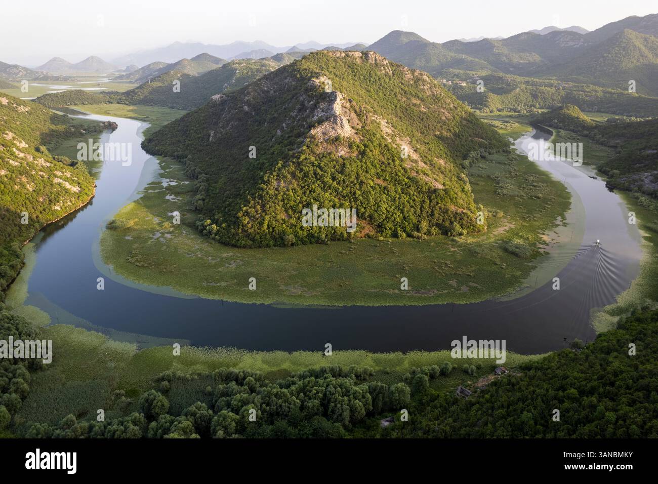 Aerial view of the winding river through a lush valley surrounded by ...