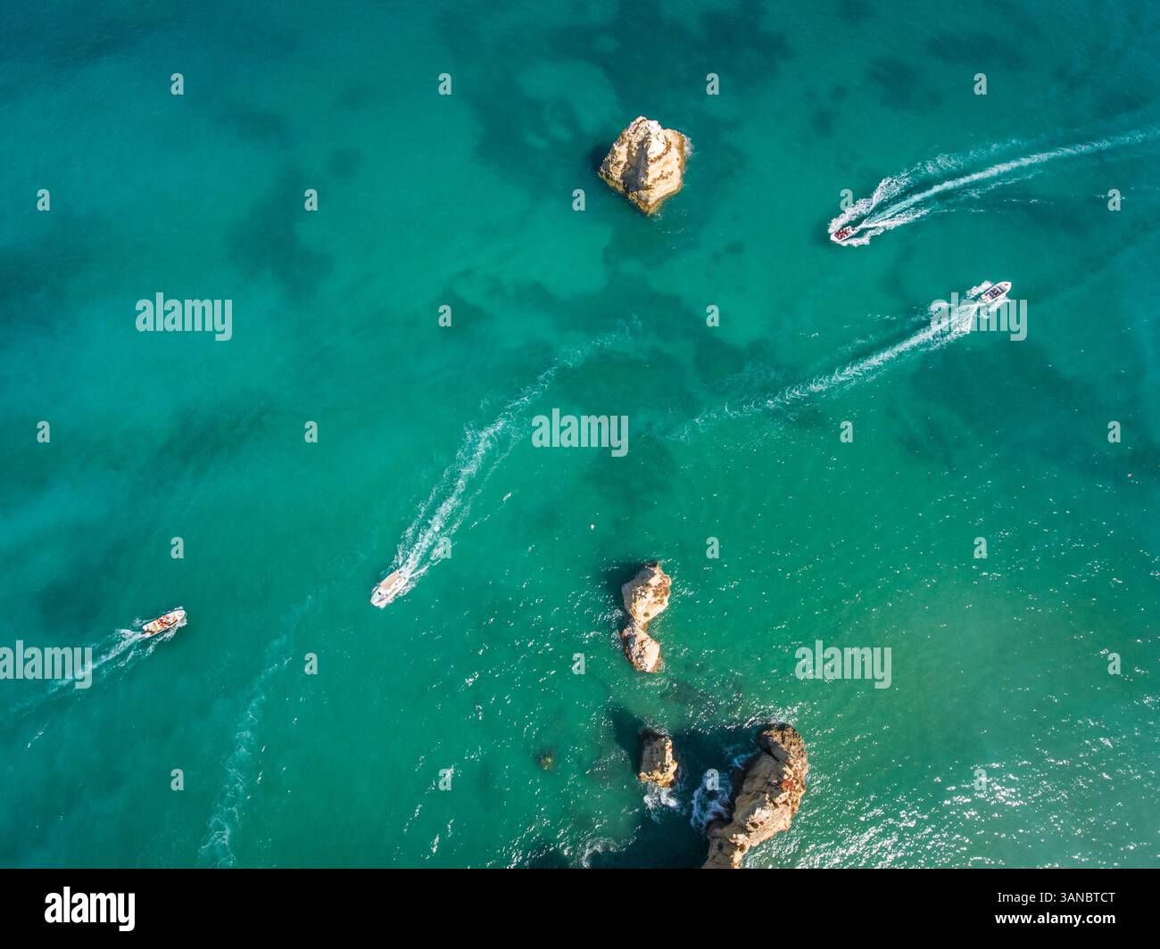 Aerial view of four boats navigating around rock pillars in the sea in ...