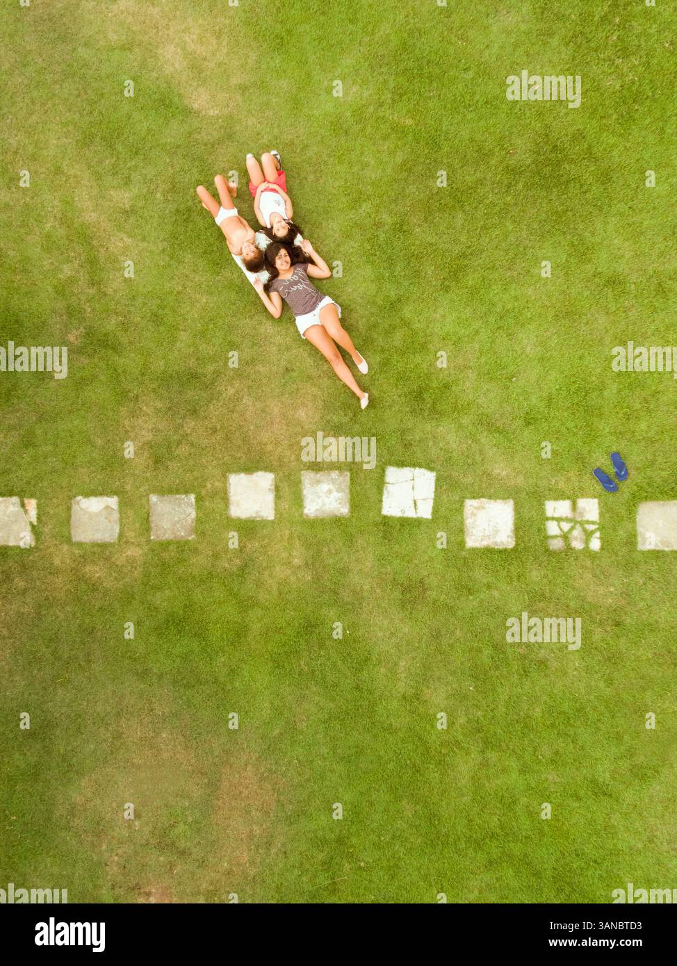 Aerial view of three girls lying in the garden during summer Stock ...