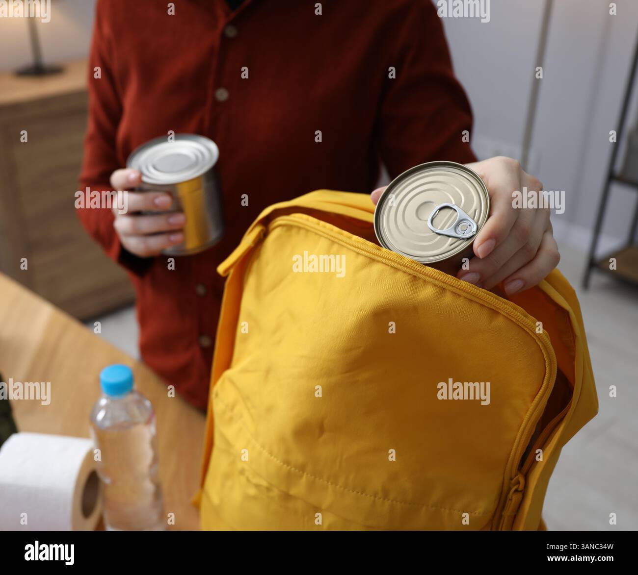 Survival kit. Woman packing different emergency supplies into backpack ...