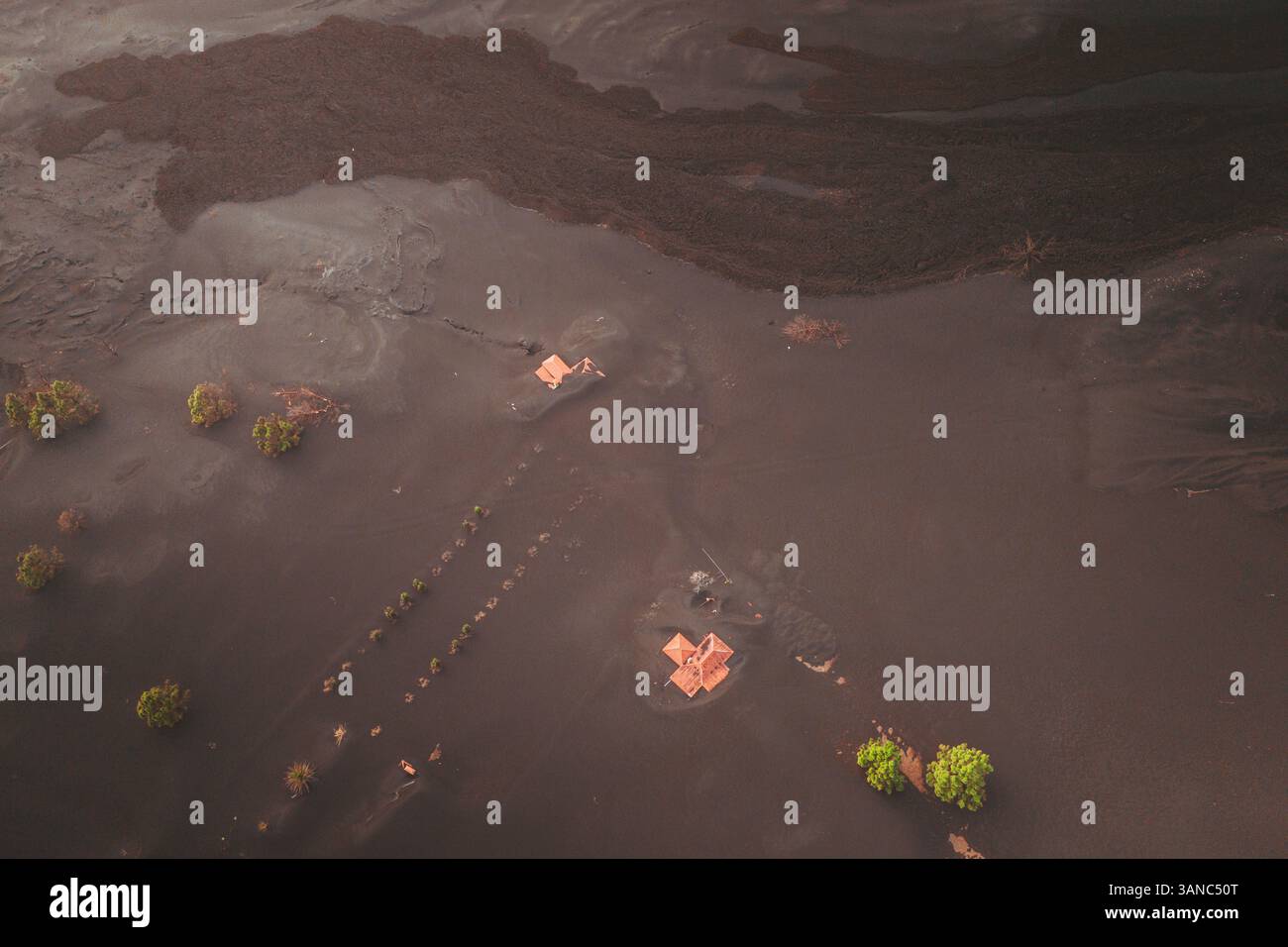 Aerial view of volcanic eruption with buried houses and flowing lava ...