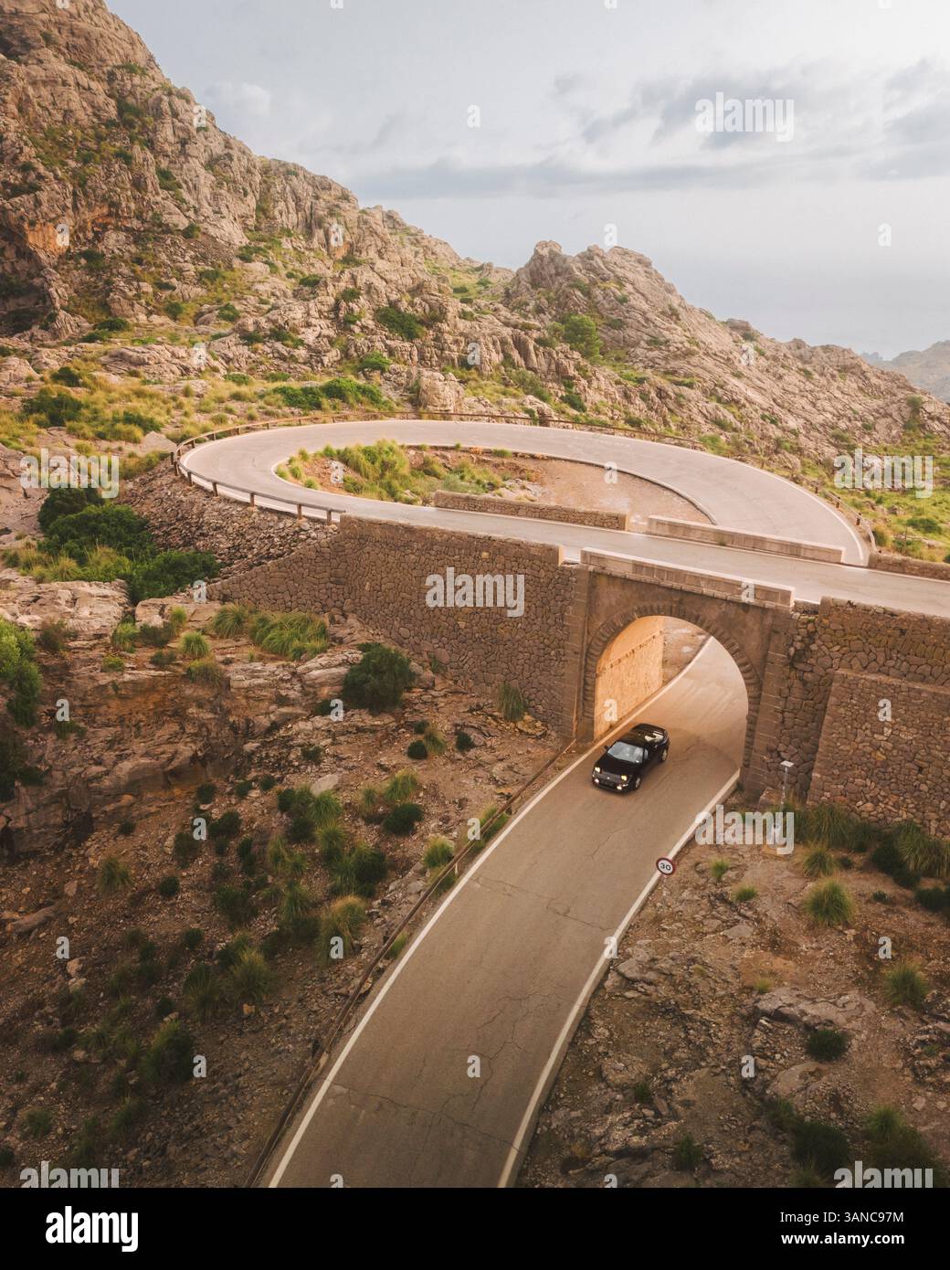 Aerial view of the winding road and picturesque bridge amidst rugged ...