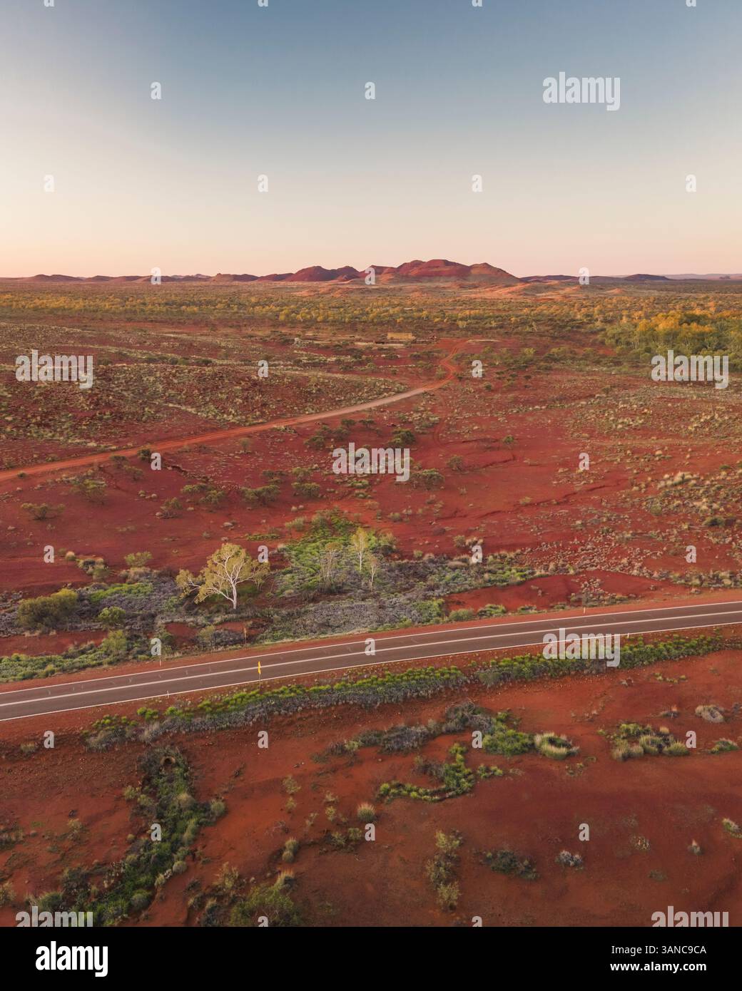 Aerial view of the arid landscape with a winding road and red earth ...