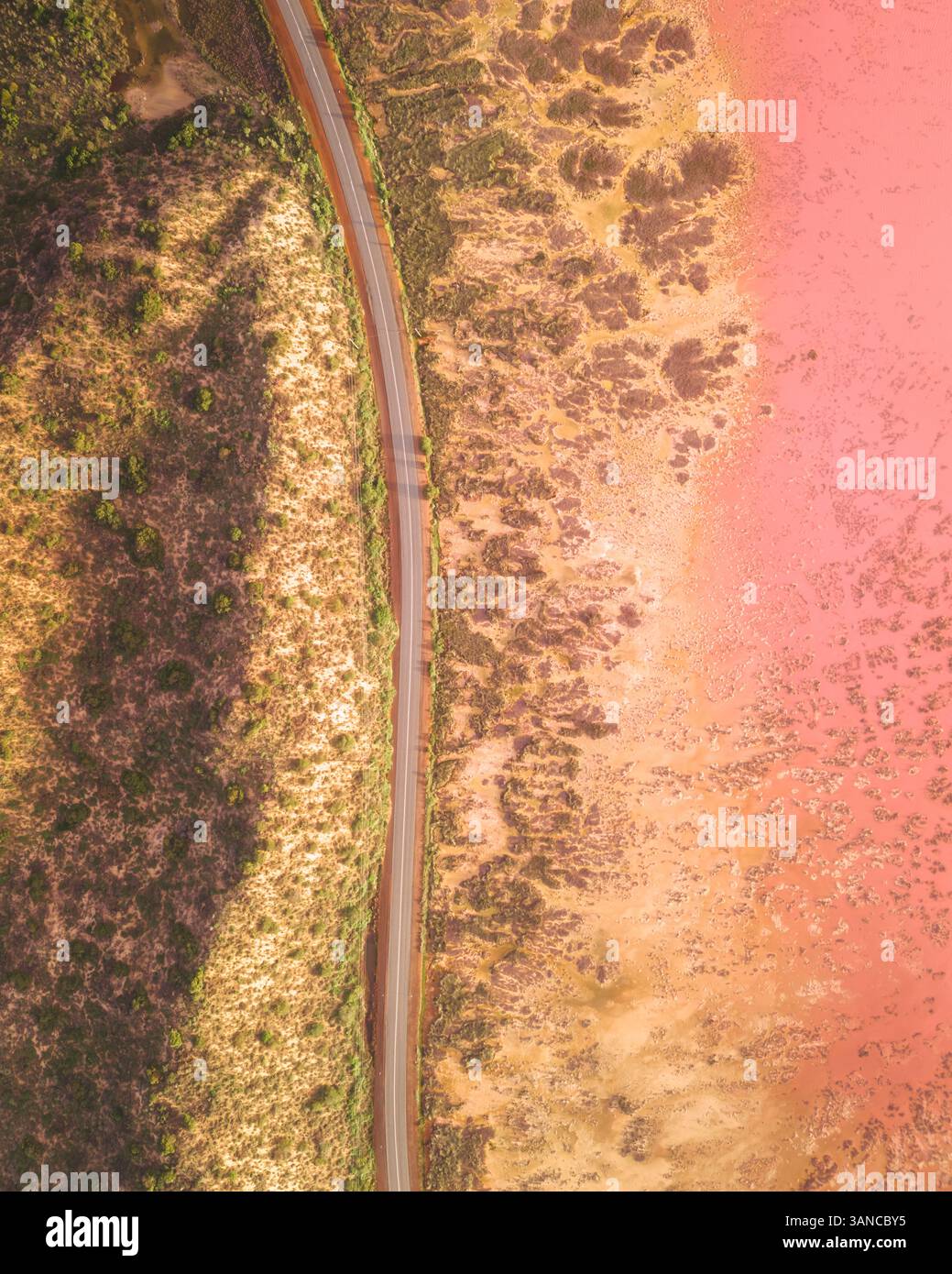 Aerial view of hutt lagoon with vibrant pink water and scenic road ...
