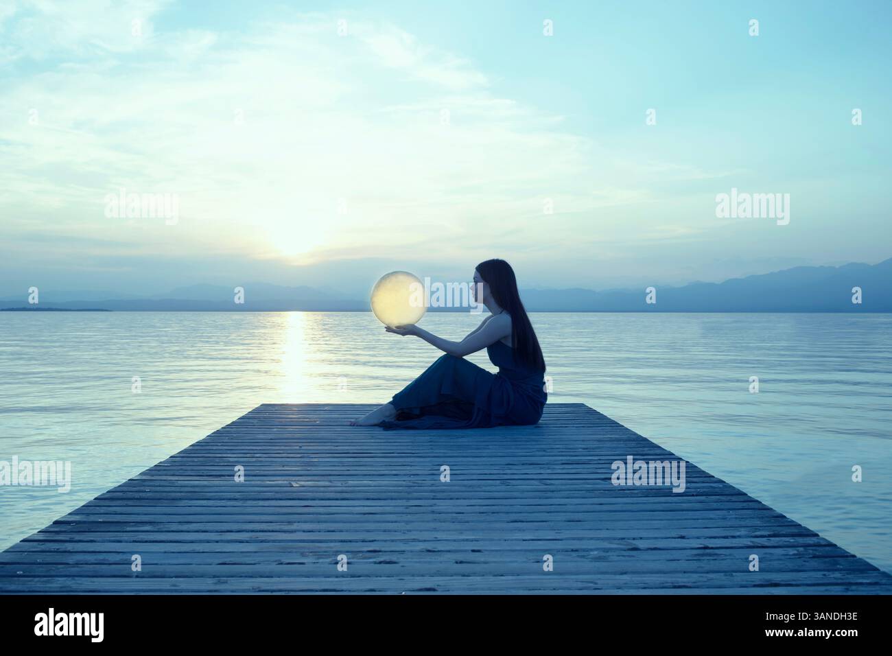 Female figure in backlight holding a moon-shaped lamp in front of a ...