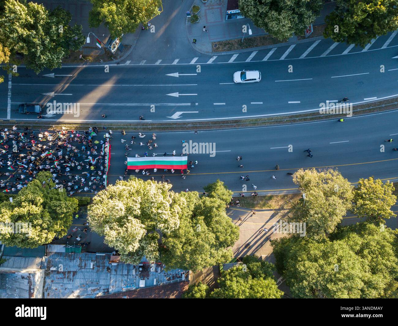 Aerial view of a vibrant procession with a gathering of people and cars ...