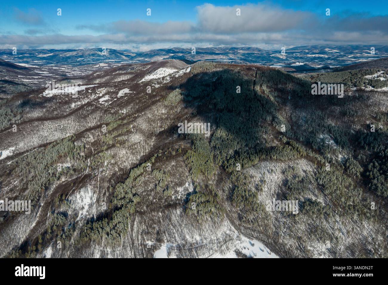 Aerial view of snowy balkan mountains with lush forests and cloudy sky ...