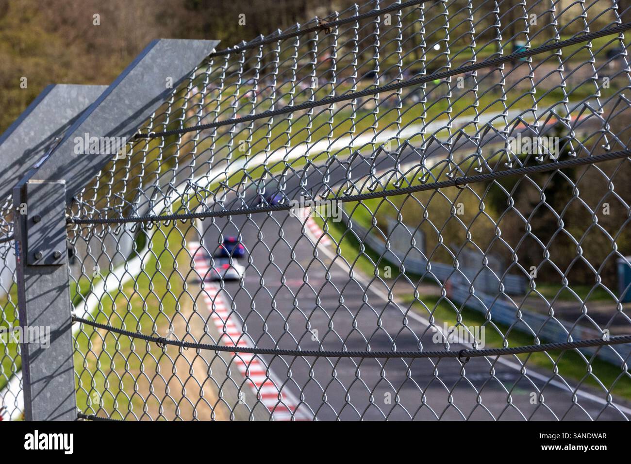 View through a safety fence at the Nürburgring race track. Blurred ...