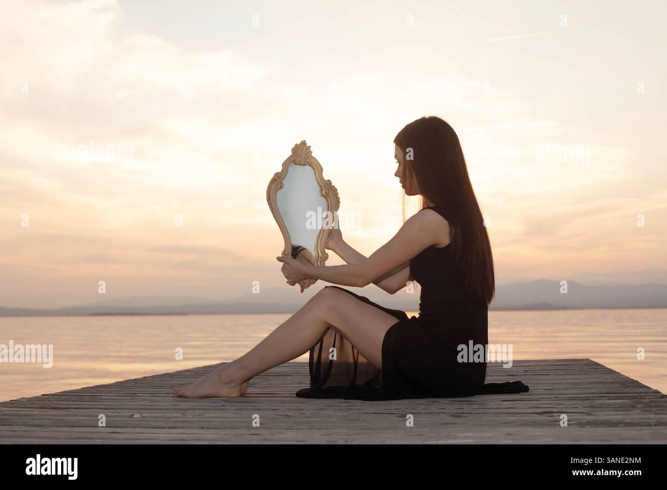 elegant woman with mirror mirrors her soul in front of a sunset ...