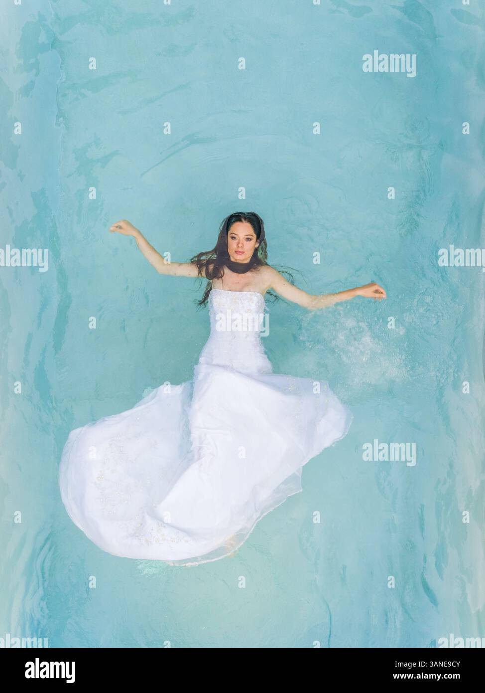 Aerial view of a beautiful woman in wedding dress floating in clear ...