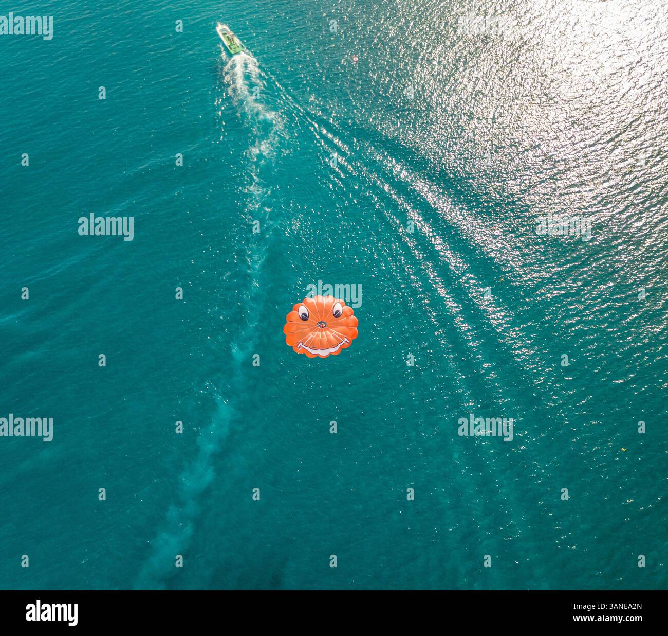 Aerial view of parachute with smiley face being pulled by boat ...