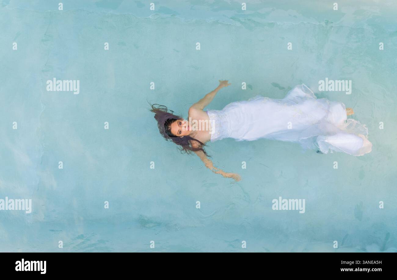 Aerial view above of an attractive woman floating in water in a wedding ...