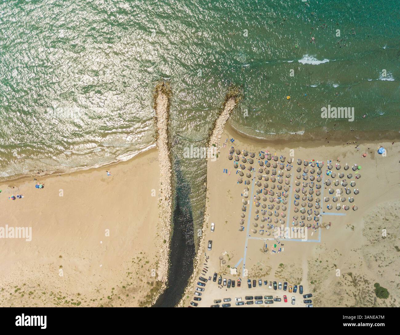 Aerial view of beach with river entering sea with straw parasols on ...