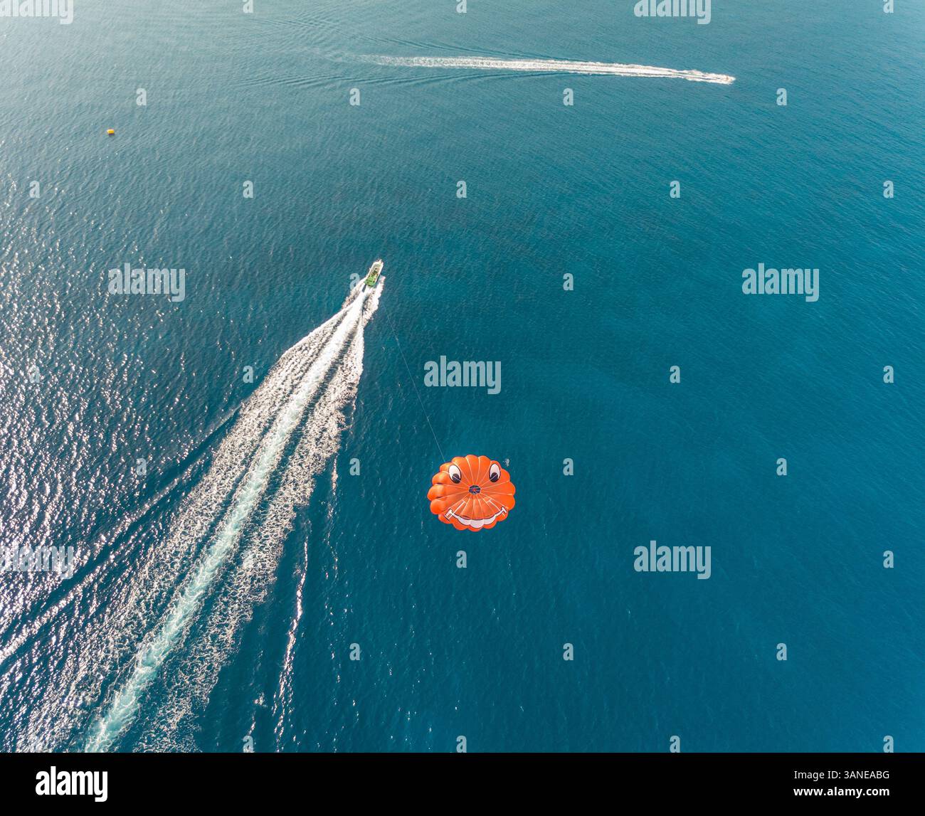 Aerial view of parachute with smiley face being pulled by boat ...