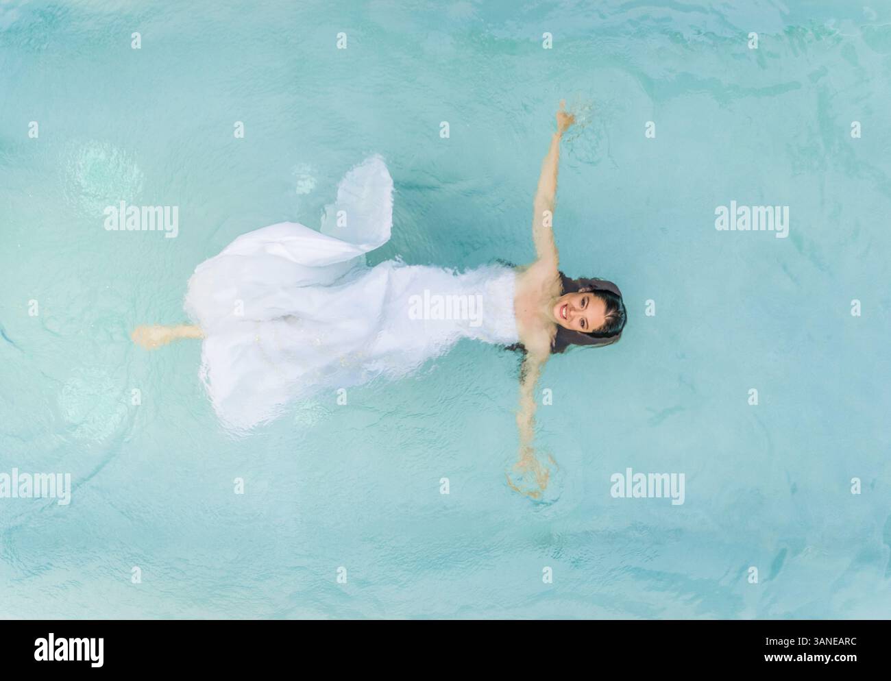 Aerial view of a pretty smiling woman in wedding dress floating in ...