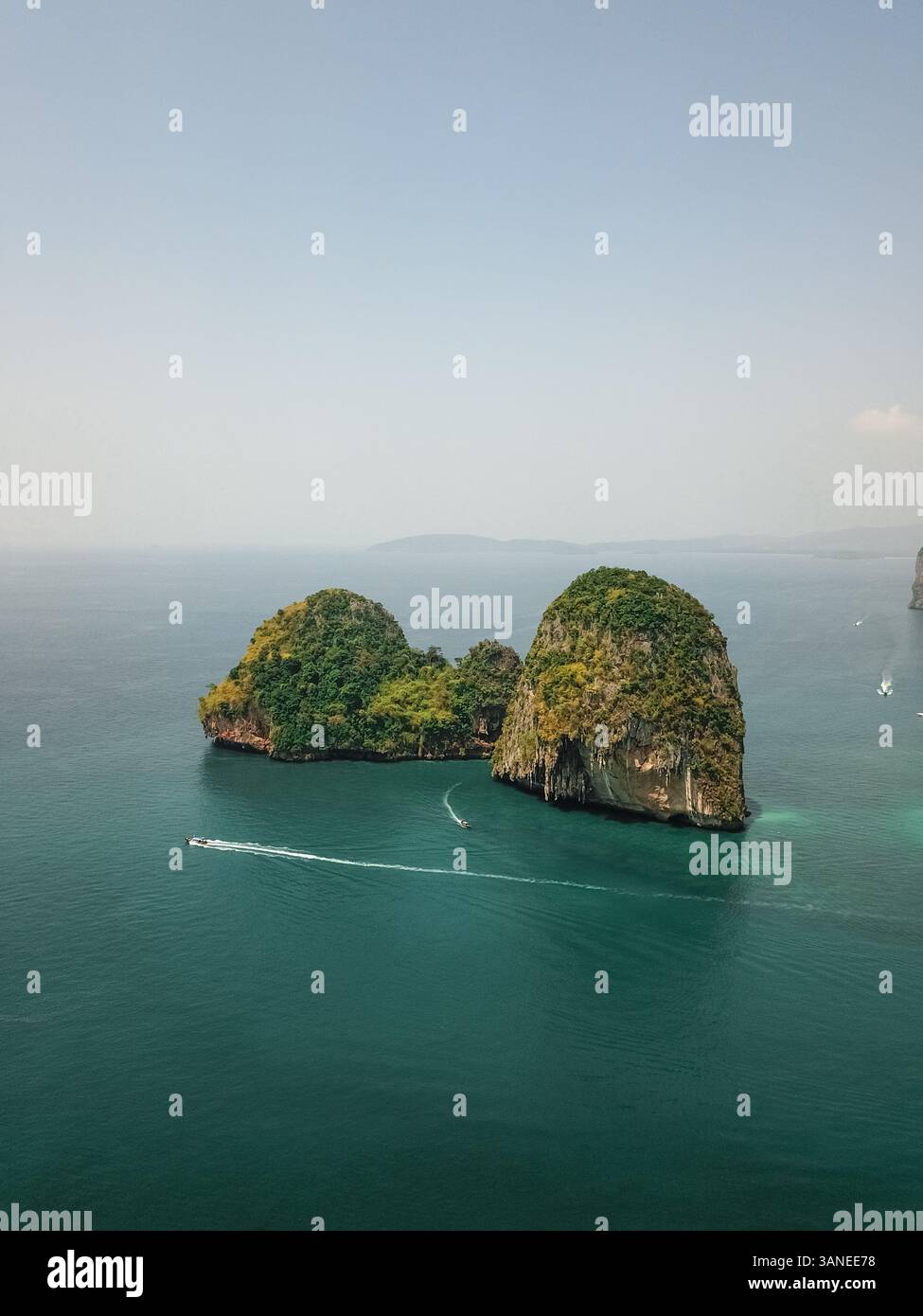 Aerial view of tiny speed boats exploring the giant limestone cliffs ...