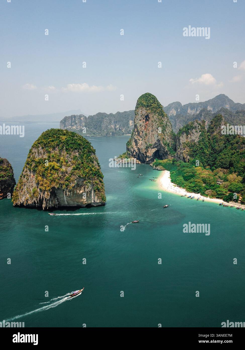 Aerial view of tiny speed boats exploring the giant limestone cliffs ...