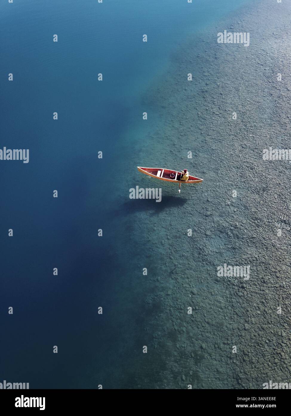 Aerial view of a person paddling Canadian canoe into deep crystal clear ...