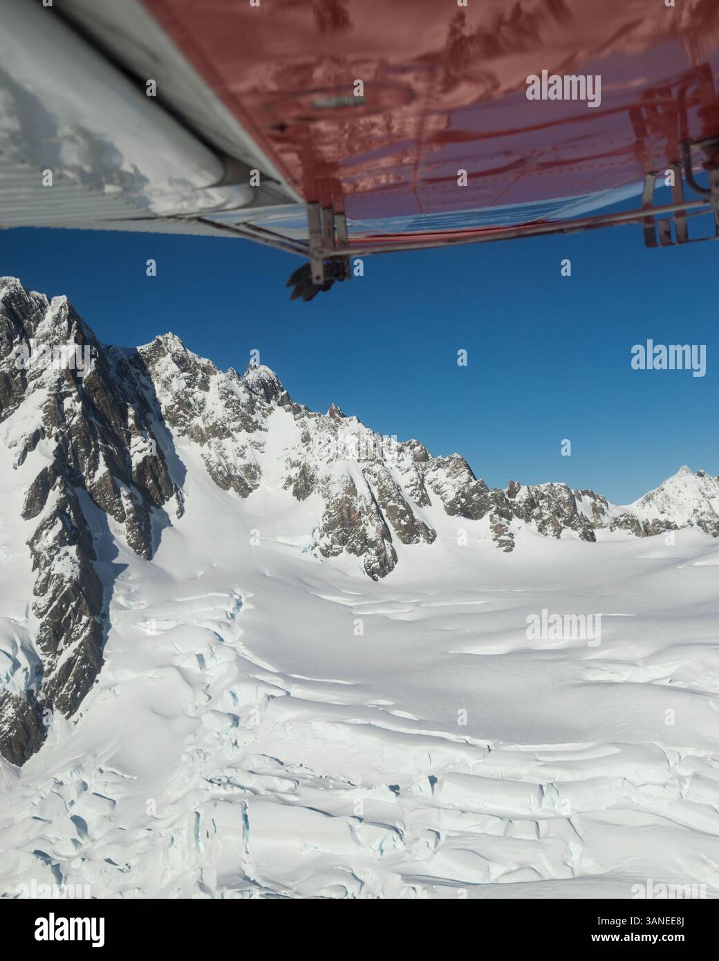Aerial view from airplane window of snowy mountain peaks and glaciers ...