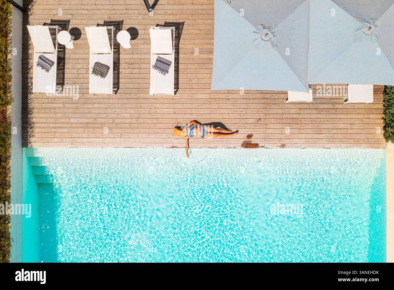 Aerial view of a blonde woman relaxing along the swimming pool of a luxury hotel, Beja, Portugal ...