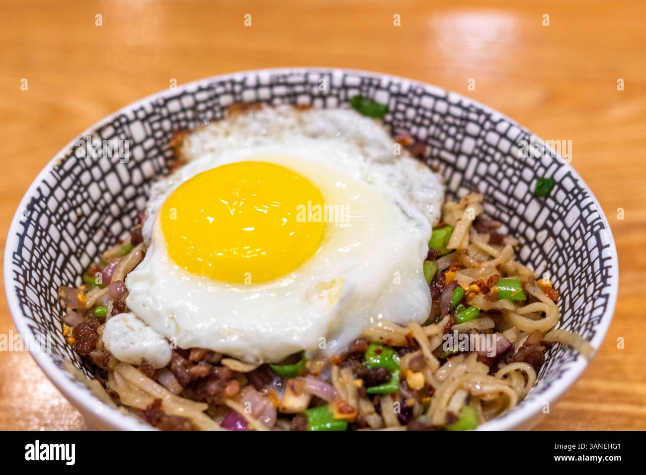 A hearty bowl of pansit or local stir-fried noodles topped with a fried ...