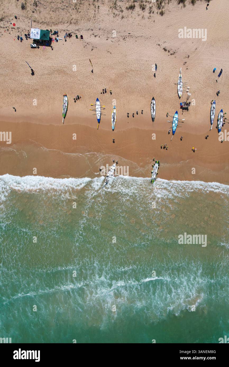 Aerial view of rowing boat race on sandy beach with beautiful ocean ...