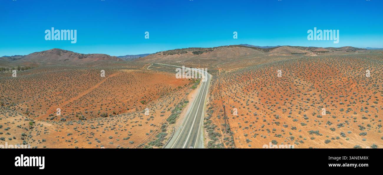 Aerial view of arid desert landscape with mountains and a winding road ...