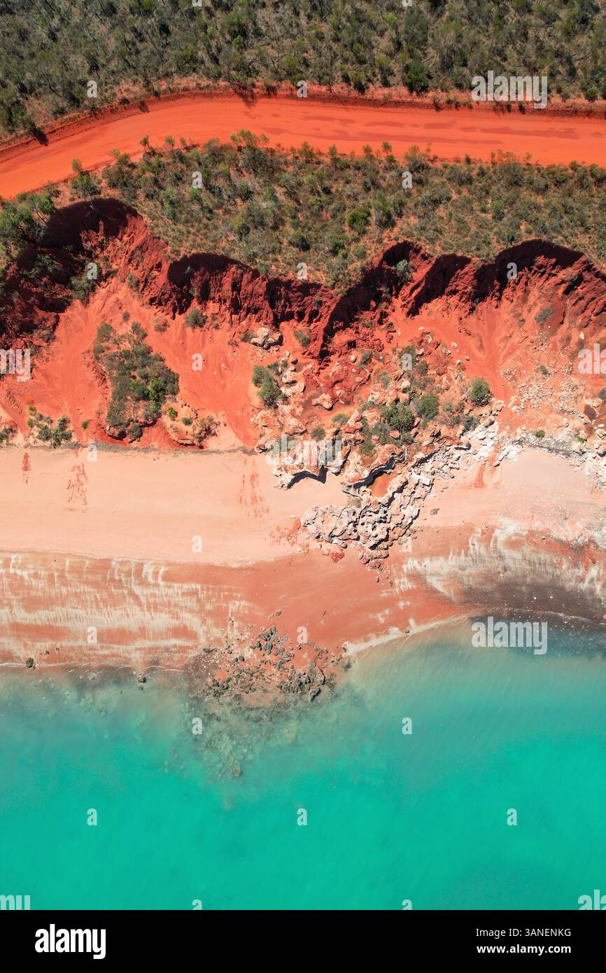 Aerial view of red sand beach and turquoise ocean with rugged cliffs ...