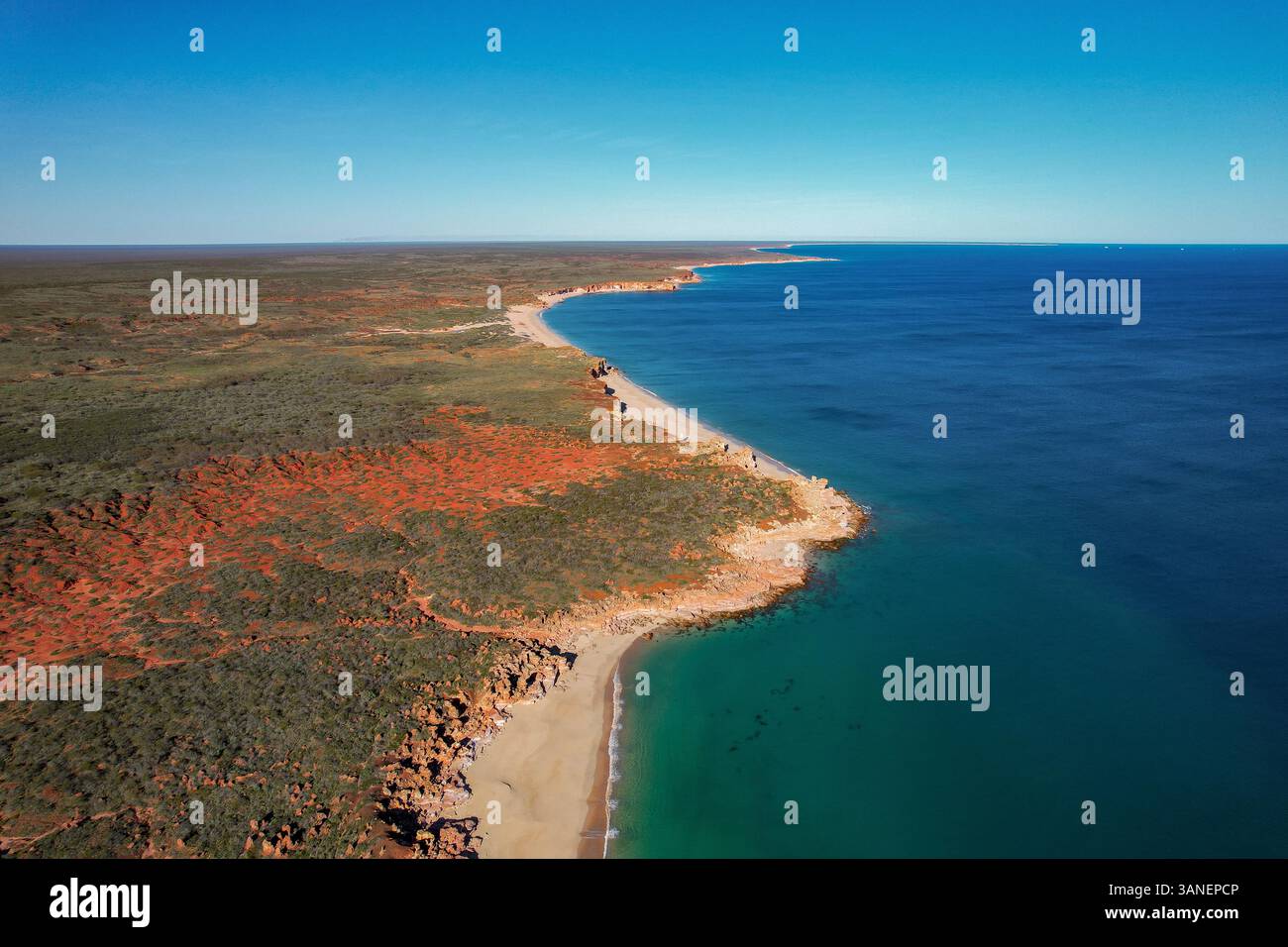 Aerial view of ochre cliff and sandy beach along the coastline with blue ocean waves, Barn Hill ...