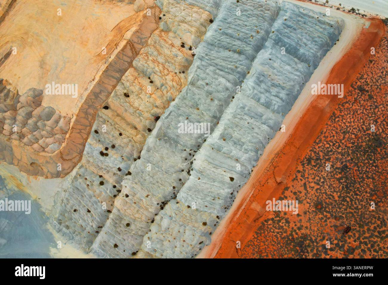 Aerial view of rugged quarry terrain with layers of red earth and ...