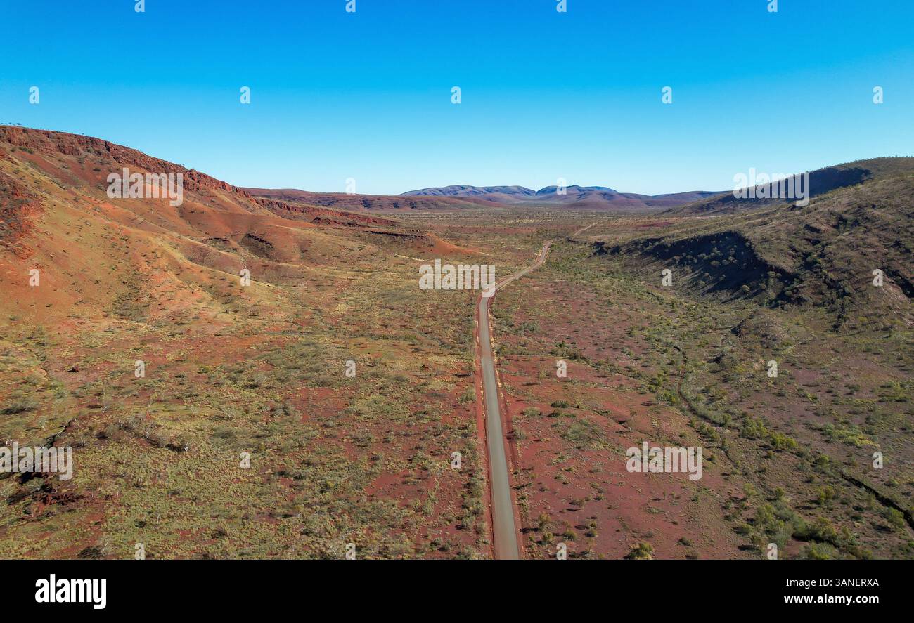 Aerial view of a beautiful desert landscape with dry dunes and a winding road in Karijini ...