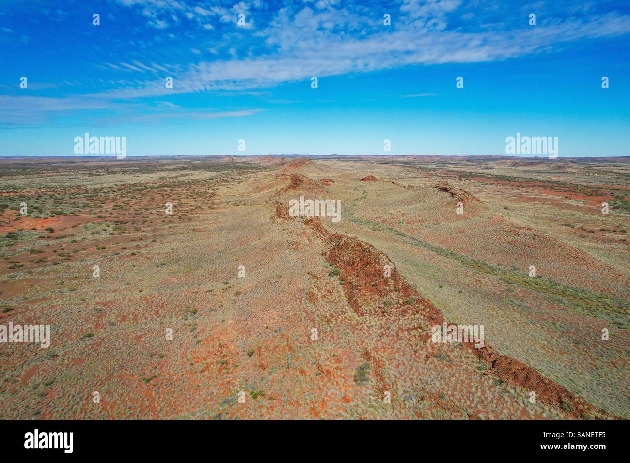 Aerial view of vast arid ridge and expansive terrain under a blue sky ...