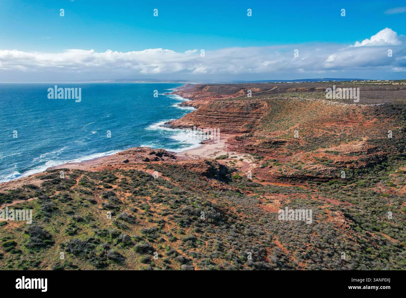 Aerial view of rugged cliffs and serene ocean waves under a blue sky ...