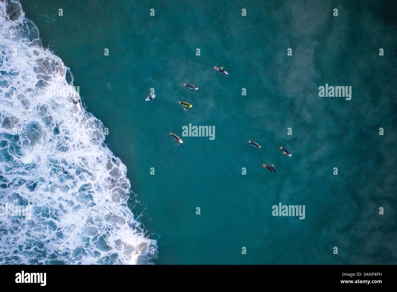Aerial view of surfers in ocean waves, The Pass Beach, Byron Bay ...