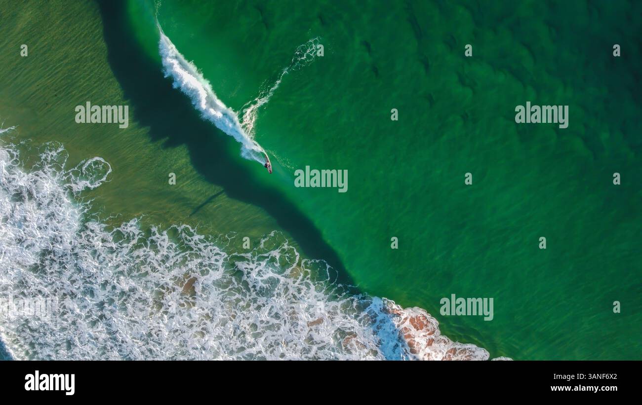 Aerial drone view of a surfer riding a wave during sunrise at Sunshine ...